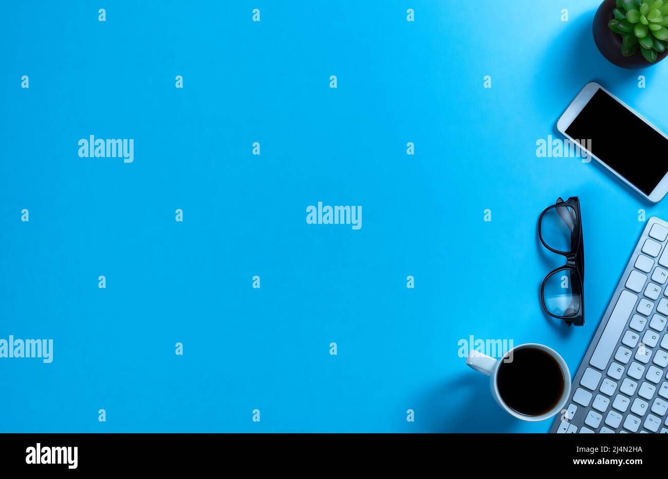 Basic work or school supplies with morning coffee on a blue desk top ...