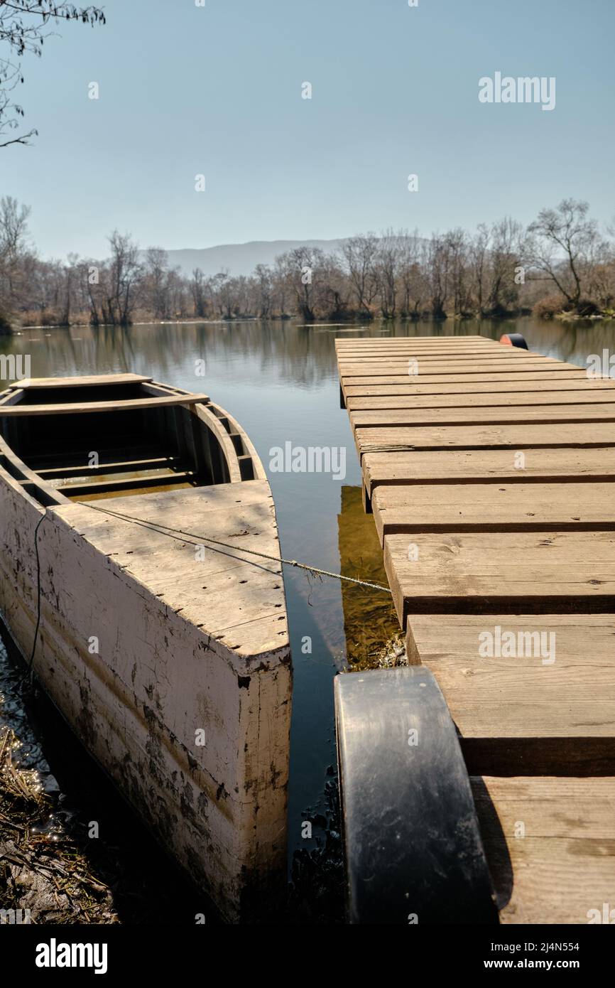 Small fishing boat and small pier made of wood with dried trees and ...
