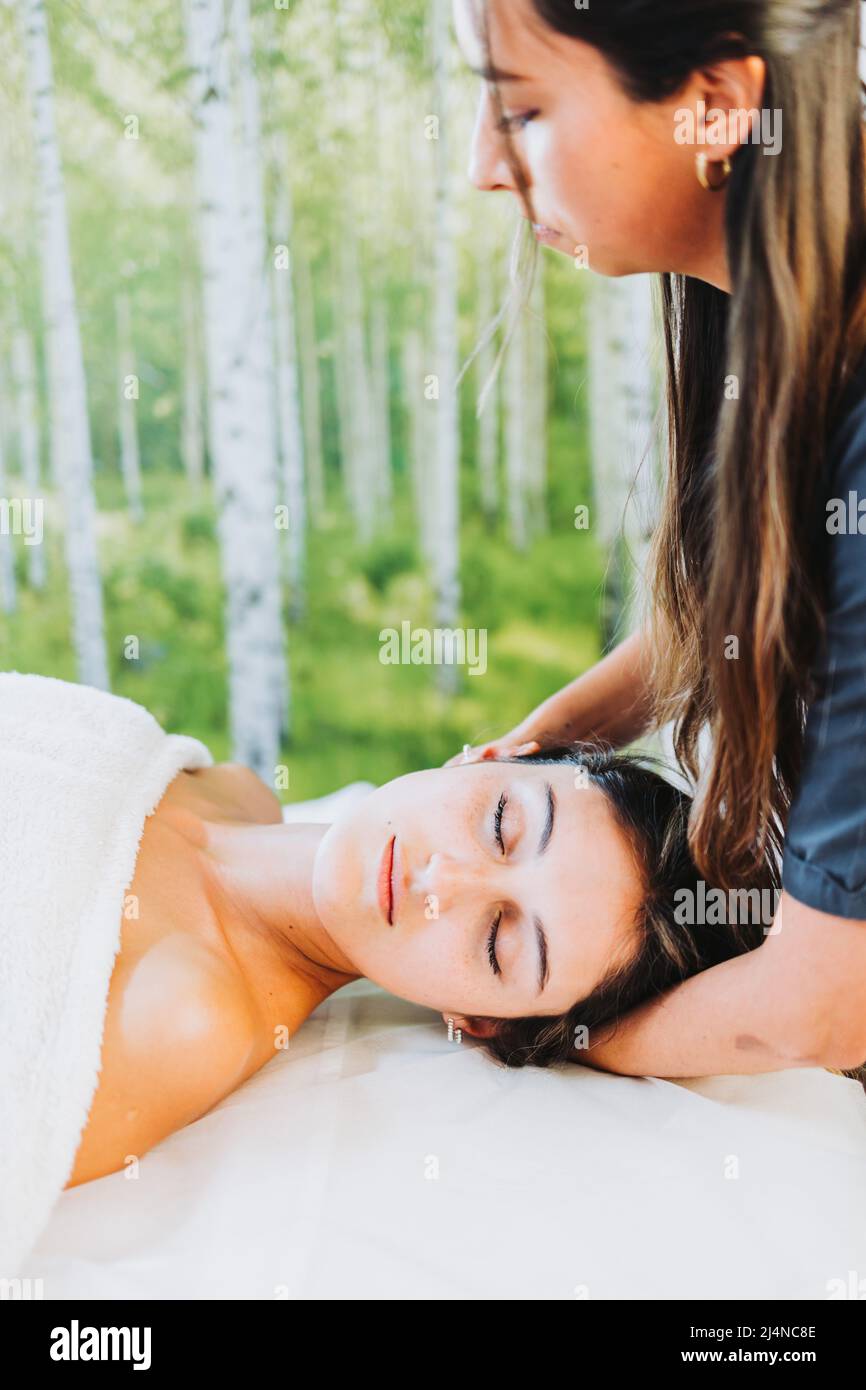Female therapist making a neck massage to a head tilted female patient ...