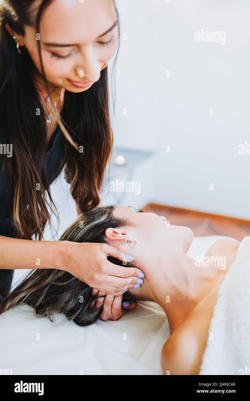 Female therapist making a neck massage to a head tilted female patient ...