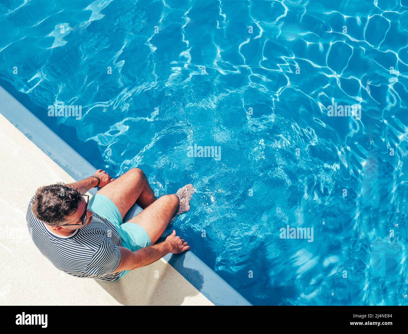 Fashionable man sitting by the pool on the empty deck Stock Photo - Alamy