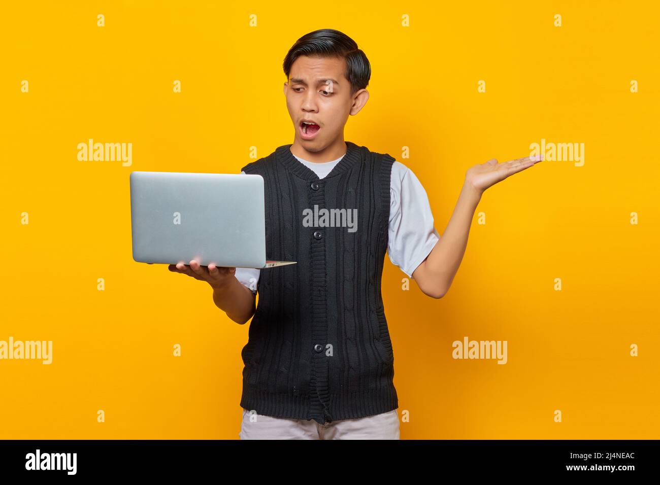 Shocked handsome young man looking at incoming email and holding laptop ...