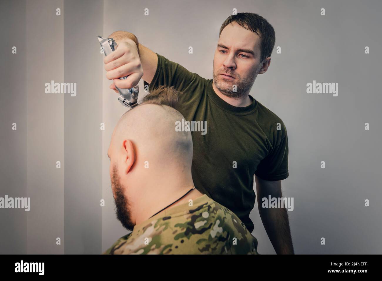 A young man in a military uniform shaves his head bald for military ...