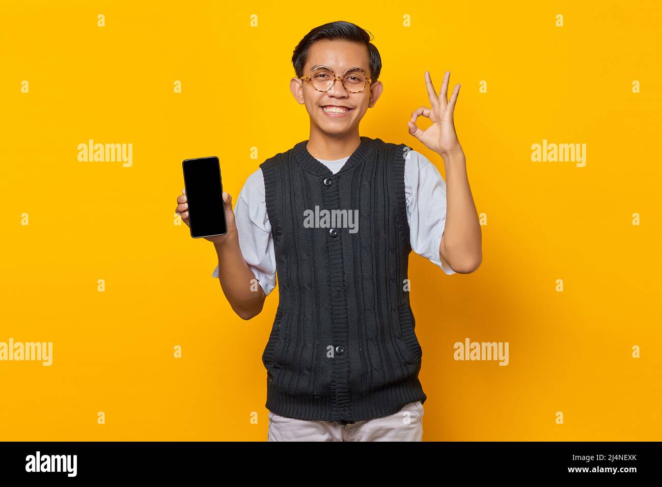 Cheerful Asian man showing smartphone blank screen and gesturing okay ...