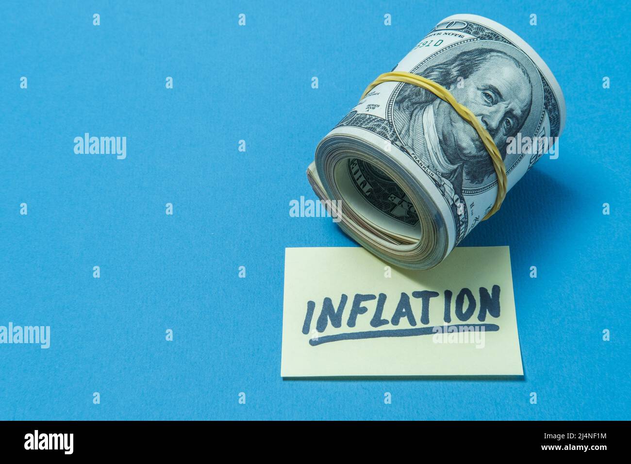 Dollars rolled into a tube with a poster that says inflation Stock ...