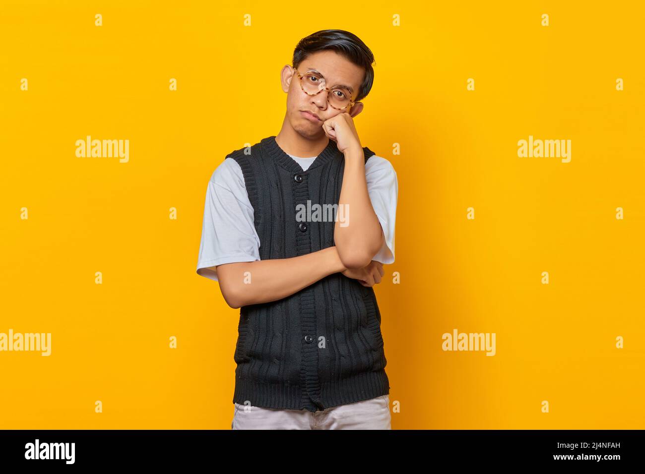 Portrait of thinking Asian man touching chin and looking at camera over ...