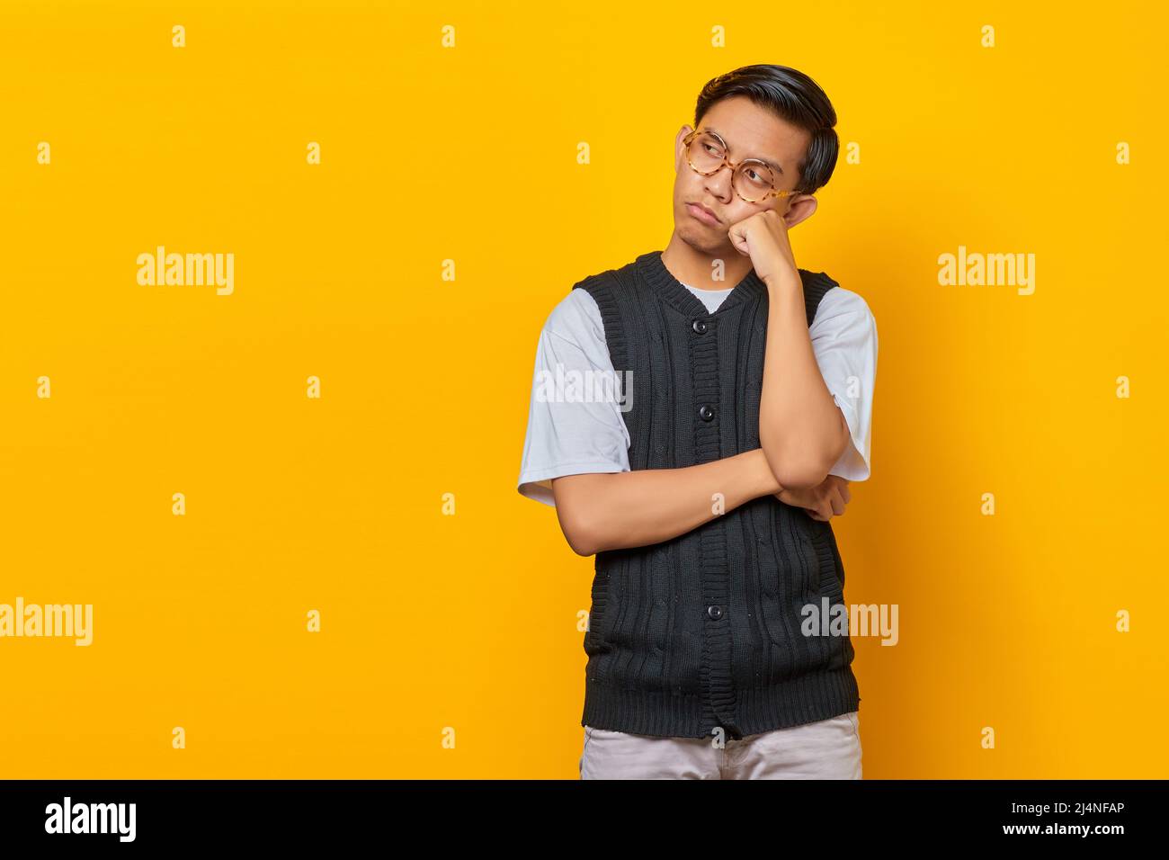 Portrait of thinking Asian man touching chin and looking at blank space ...