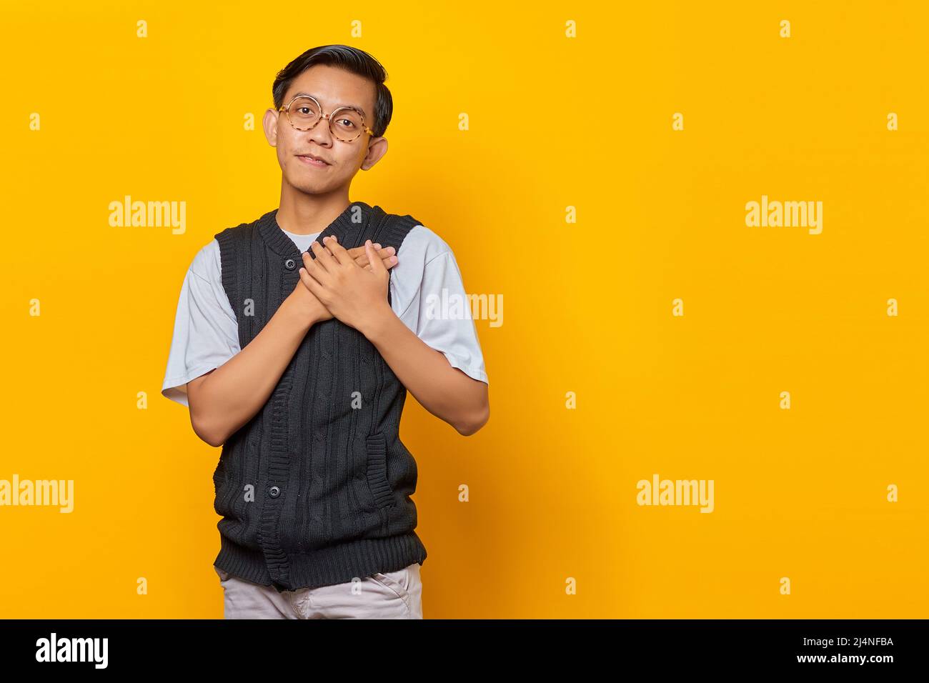 Happiness young Asian man keeping both palms on chest isolated over ...