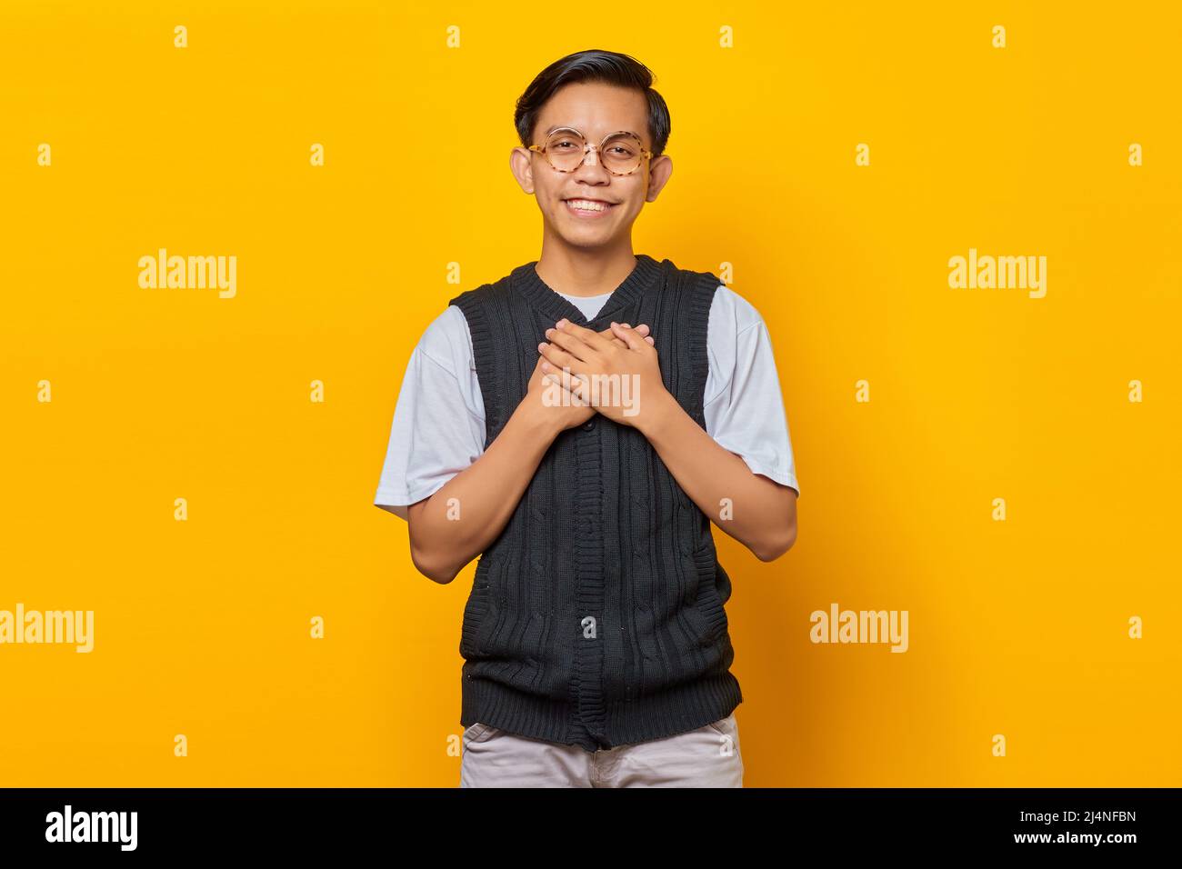 Happiness young Asian man keeping both palms on chest isolated over ...