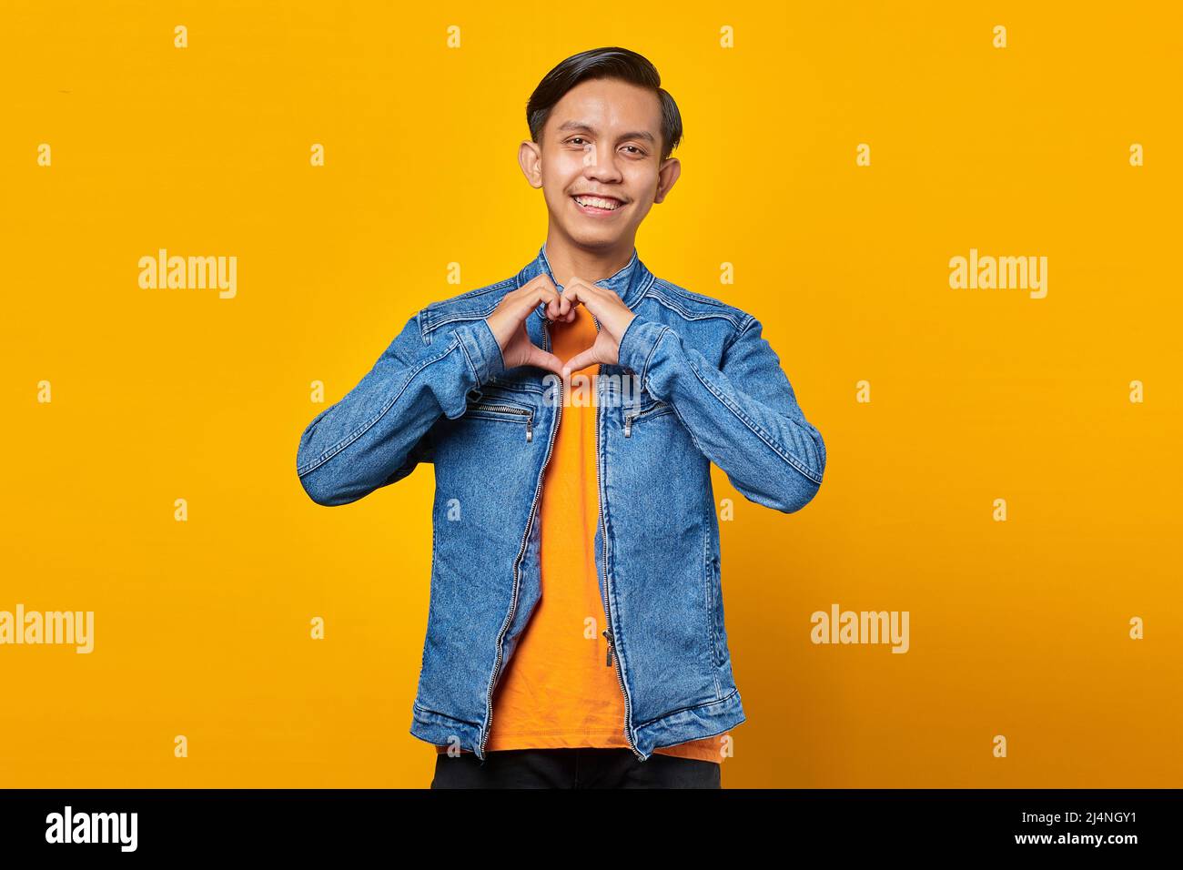 Portrait of cheerful young Asian man making heart sign with fingers ...