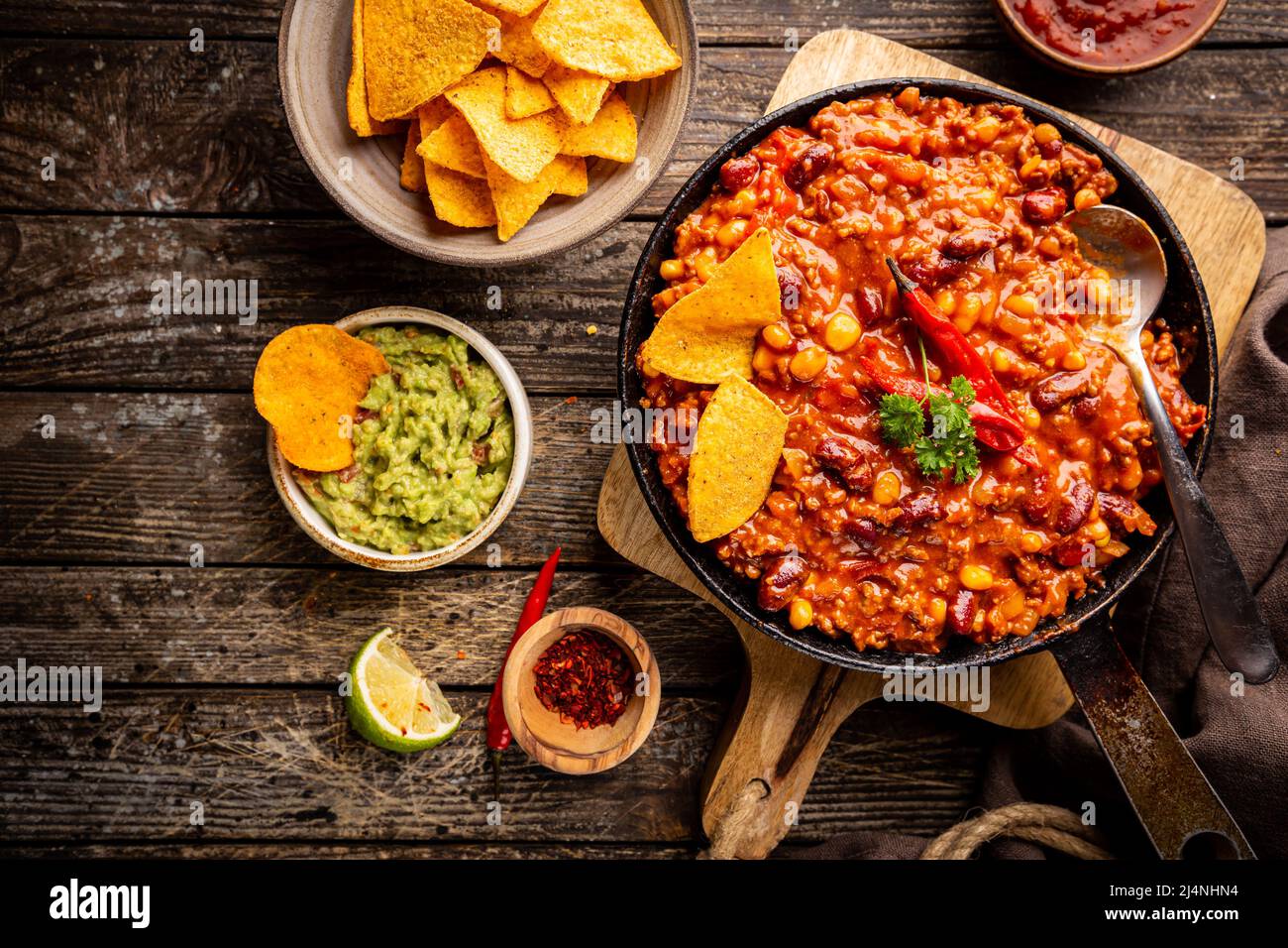 Mexican hot chili con carne in a pan with tortilla chips on dark ...