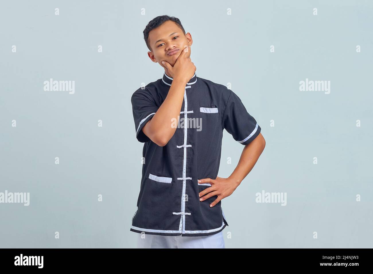 Portrait of Asian young man wearing taekwondo kimono asking thinking ...