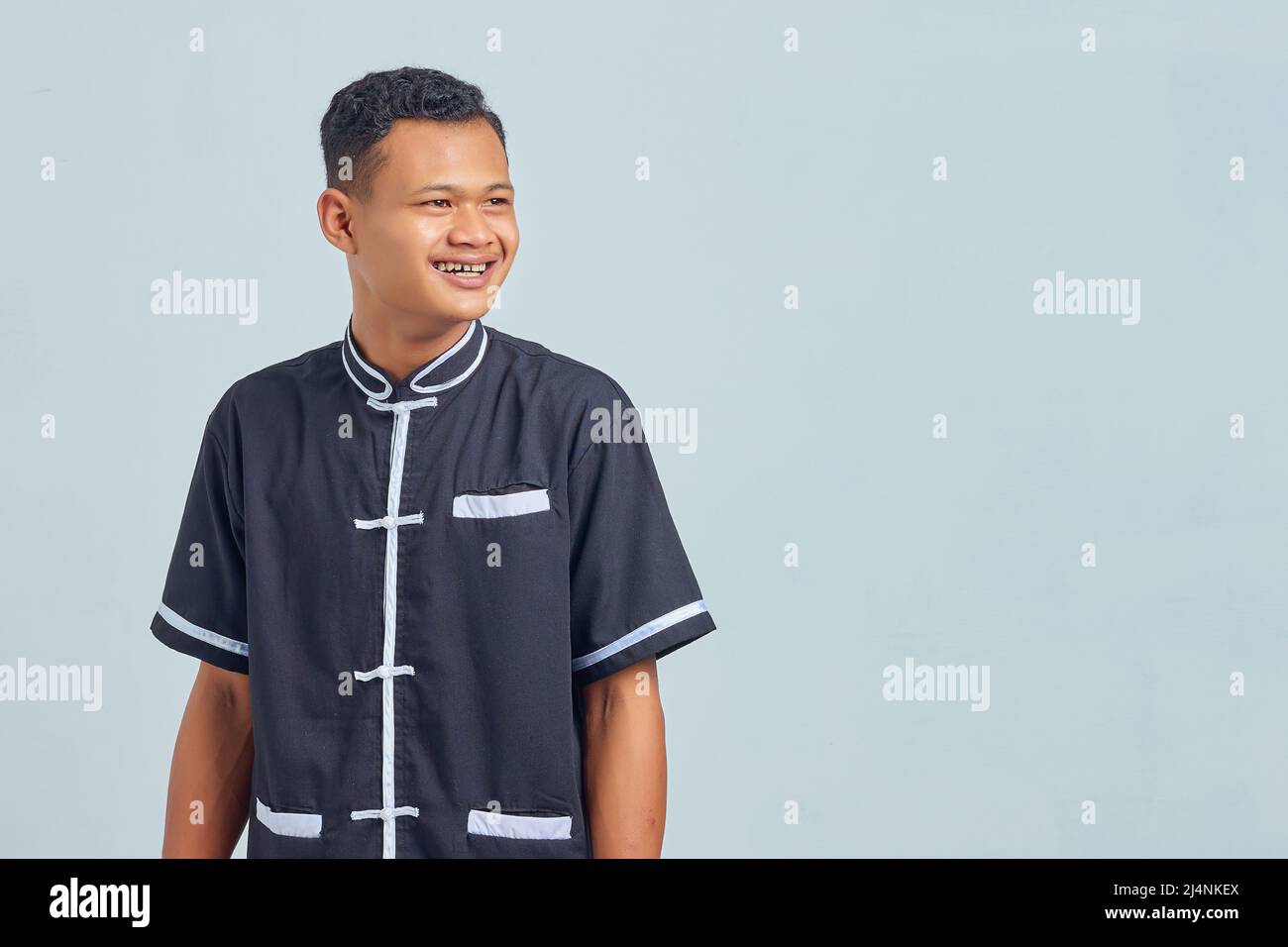 Portrait of Asian young man wearing karate uniform laughing at funny ...