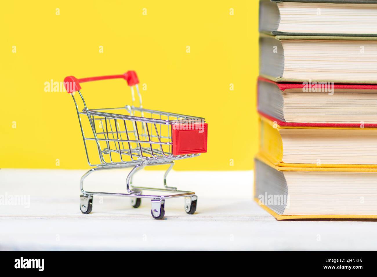Back to school. A mini shopping cart and a stack of books with an open ...