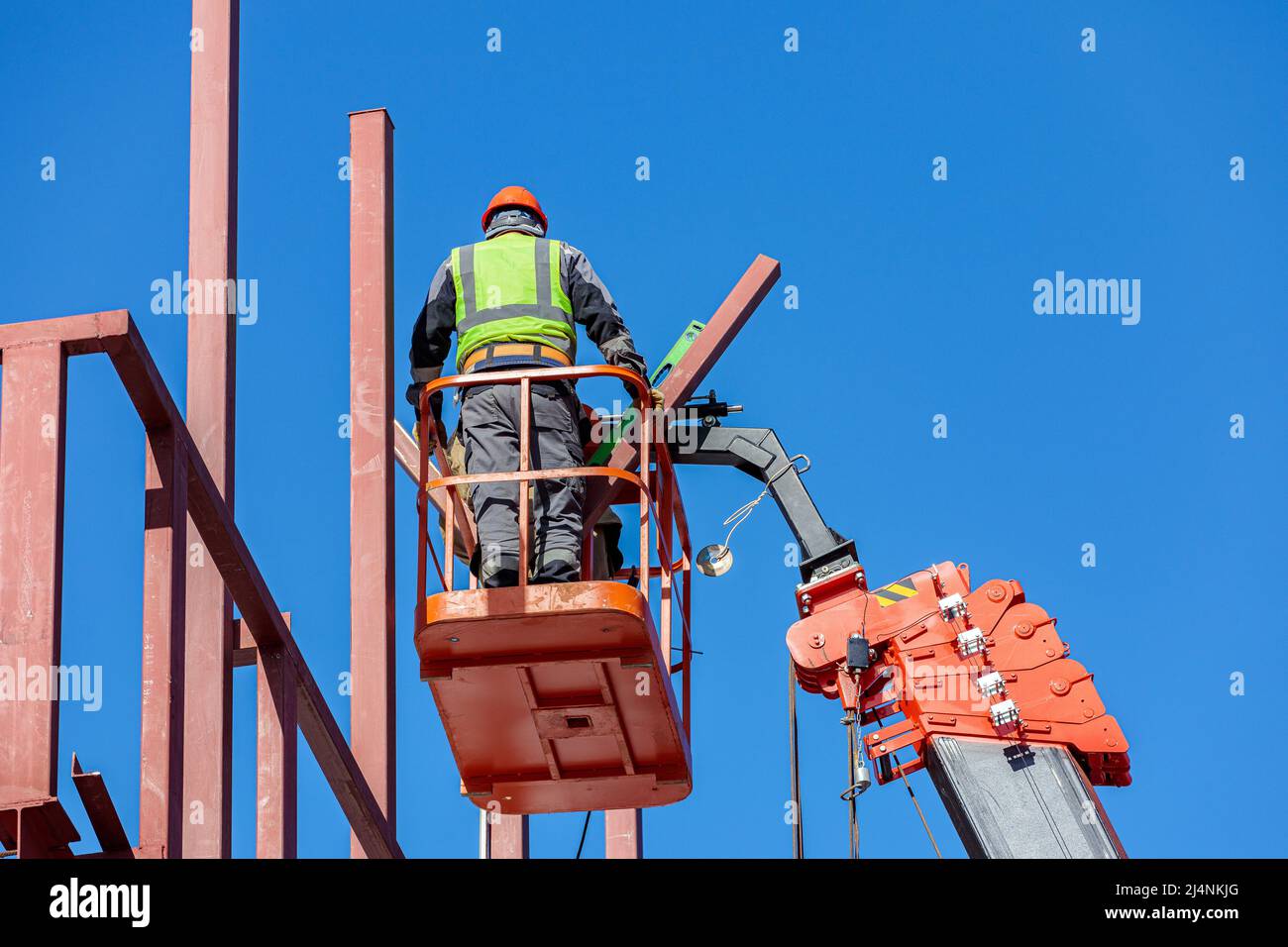 Male builders work at height in a lifting cradle, creating the iron ...