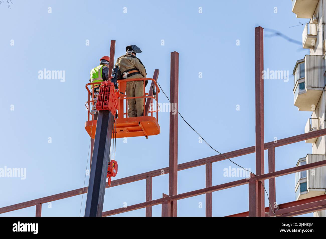 Male builders work at height in a lifting cradle, creating the iron ...