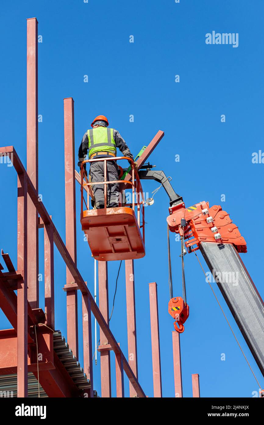 Male builders work at height in a lifting cradle, creating the iron ...