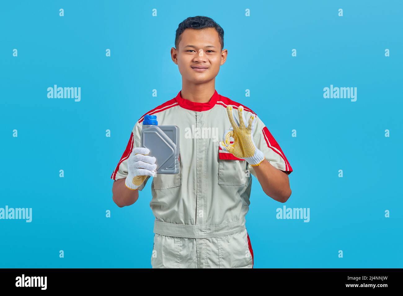 Portrait of smiling young Asian mechanic showing engine oil plastic ...