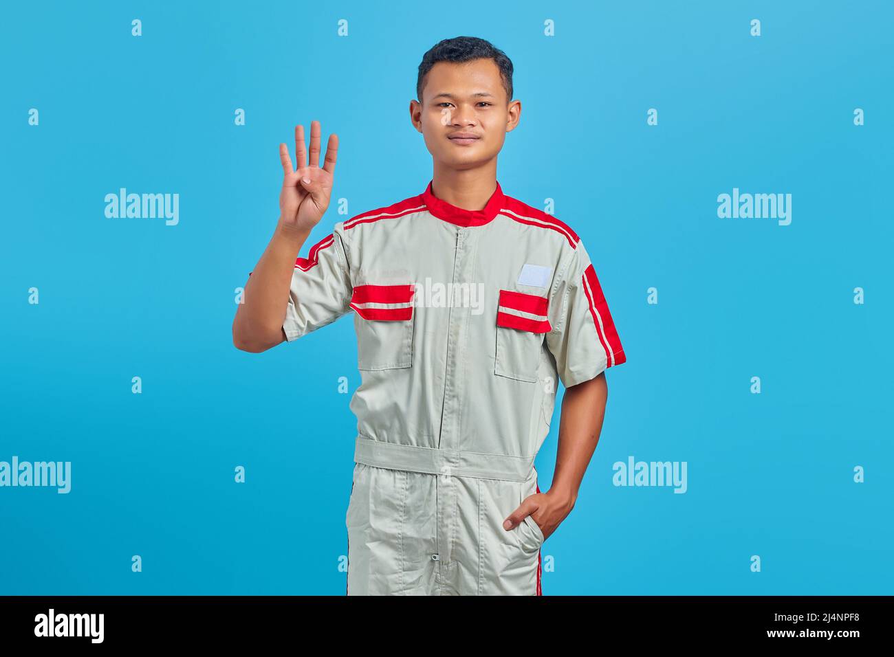 Portrait of smiling young Asian mechanic making number four sign with ...