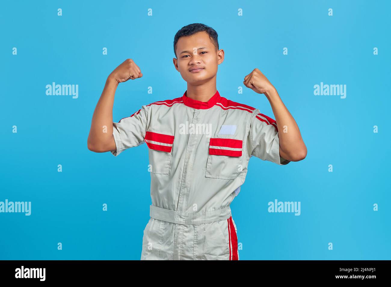 Attractive young asian mechanic showing muscles with smiling expression ...