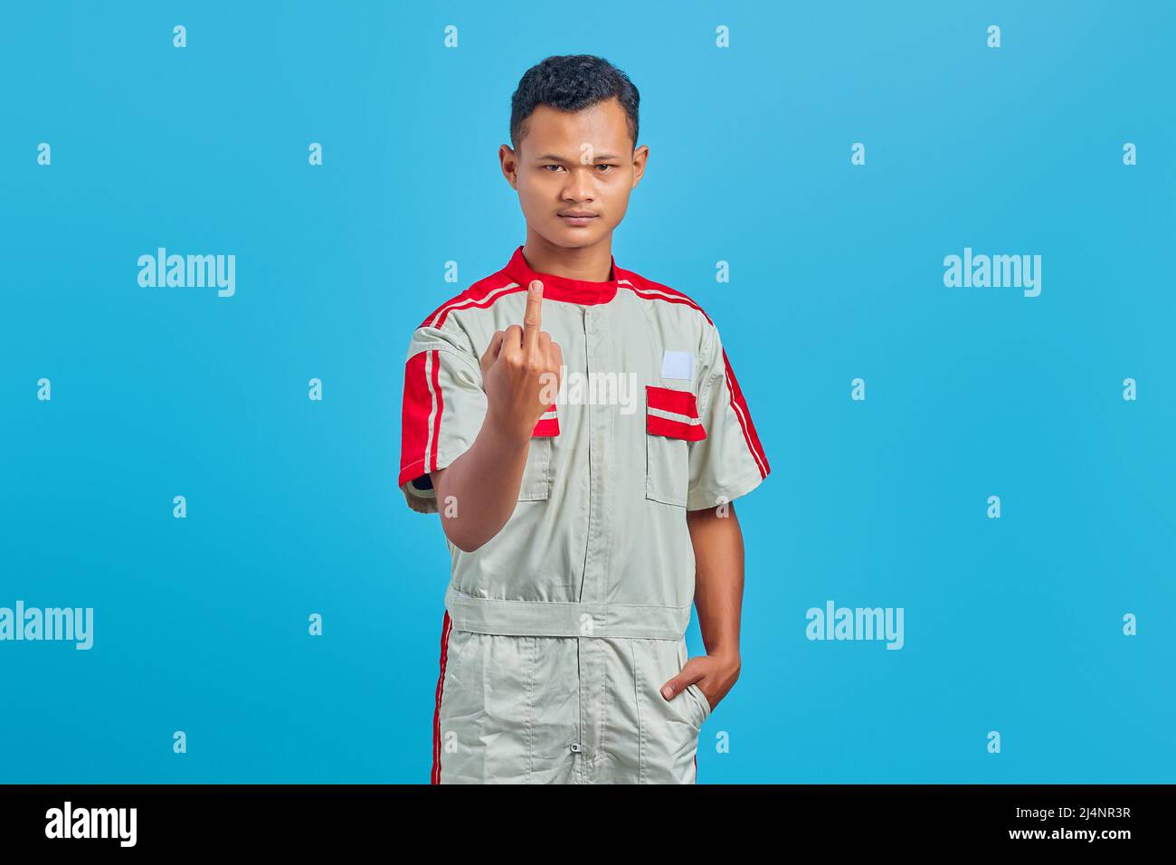 Portrait of angry young Asian mechanic showing middle finger to camera ...