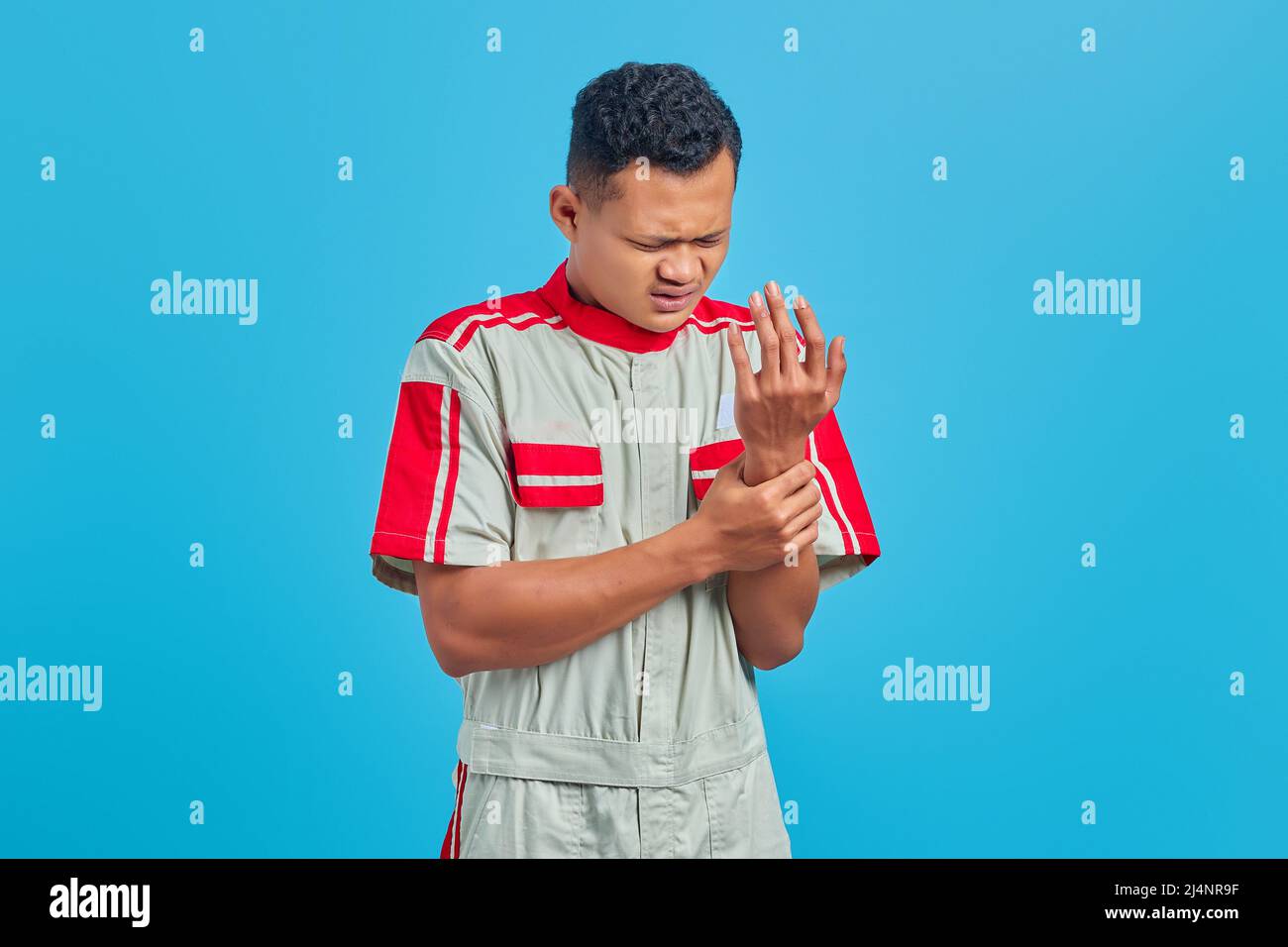 Portrait of young Asian mechanic suffering from pain in hands and ...