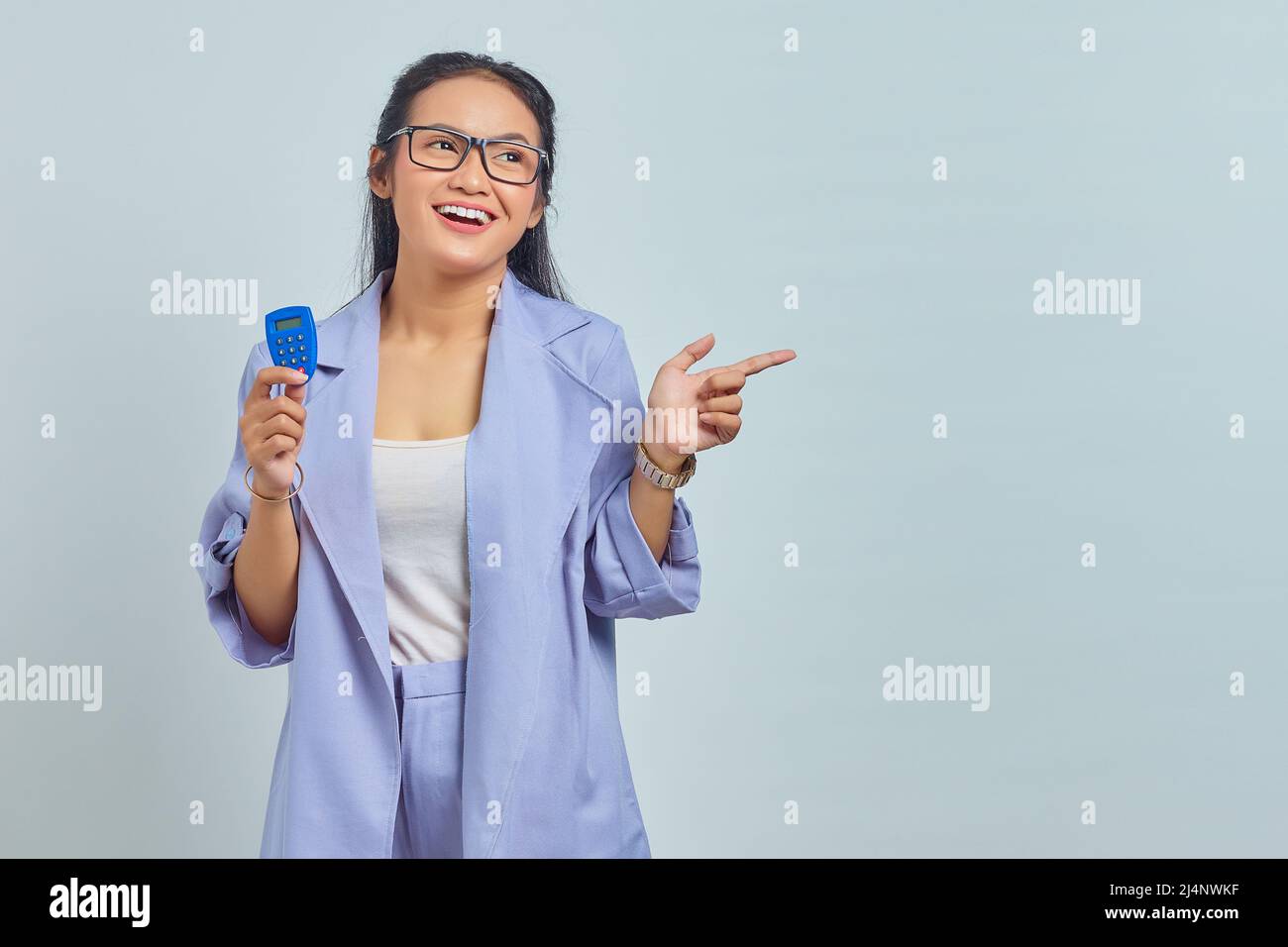 Portrait of cheerful young Asian woman holding banking token and ...