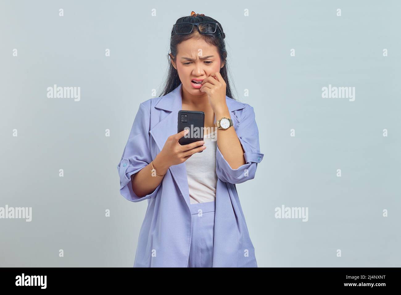 Portrait of young Asian woman using cell phone looking stressed and ...