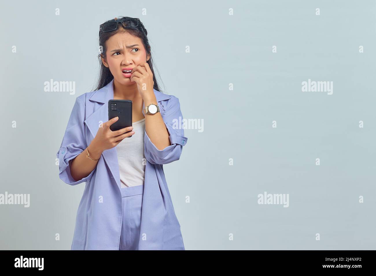 Portrait of young Asian woman using cell phone looking stressed and ...