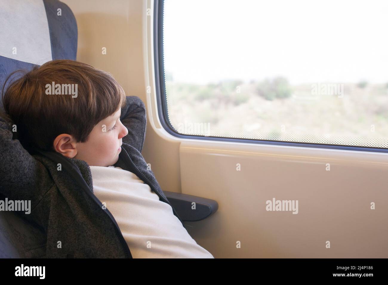 Child traveling by train comfortably. He is enjoying the landscape ...