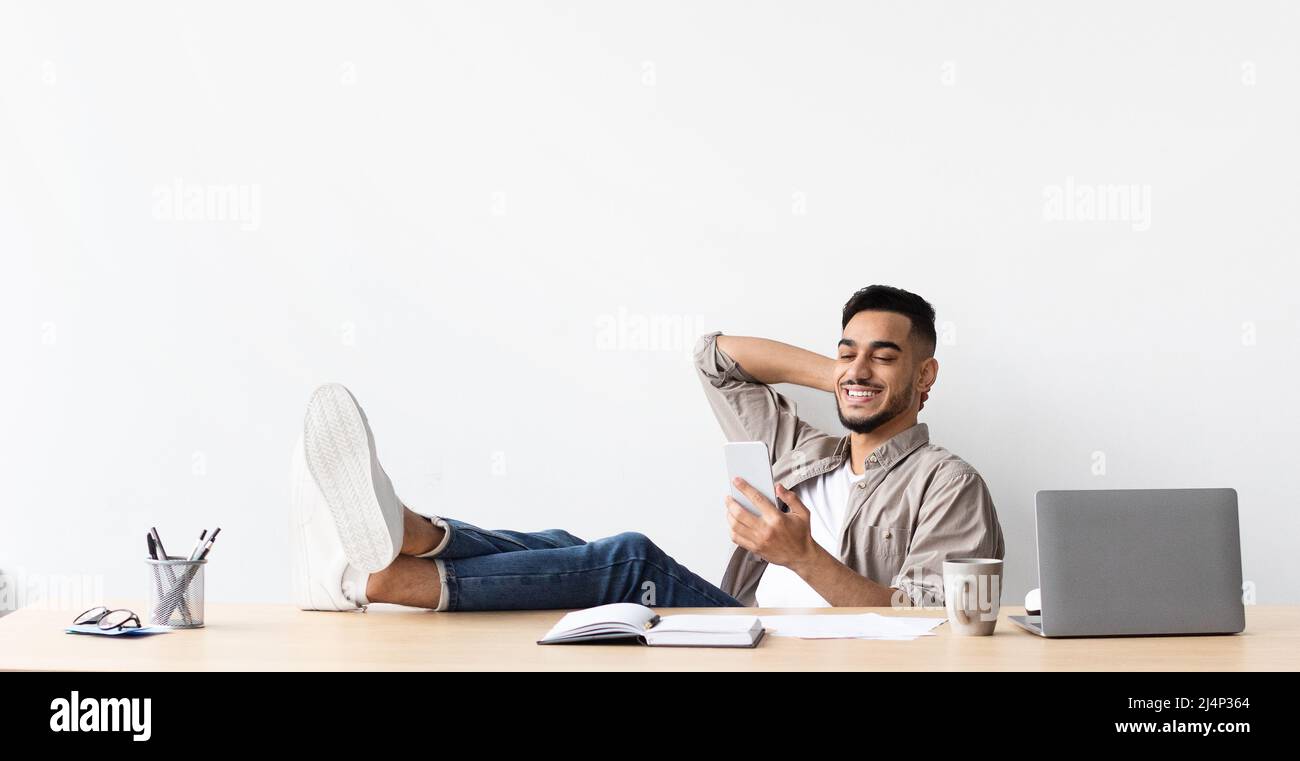 Arab man resting feet on table using mobile phone Stock Photo - Alamy