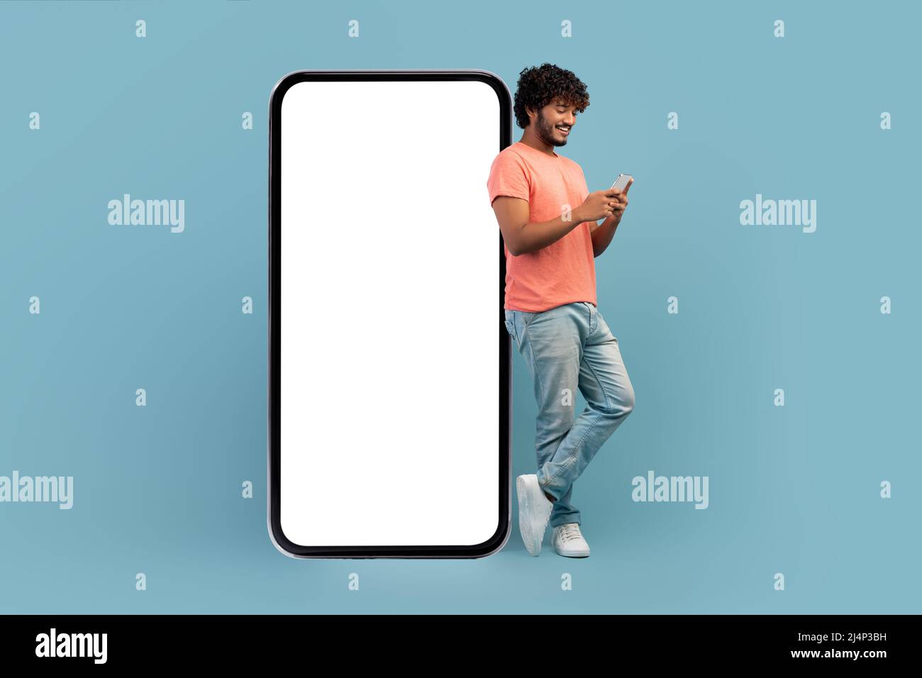 Cool indian guy leaning on huge smartphone, using cell phone Stock ...