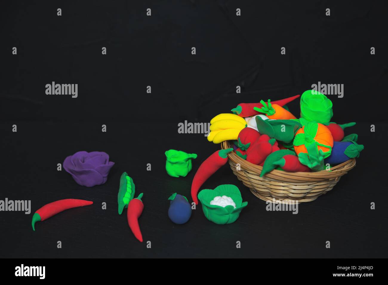 Basket of plasticine vegetables and fruits on a black background. Fresh ...