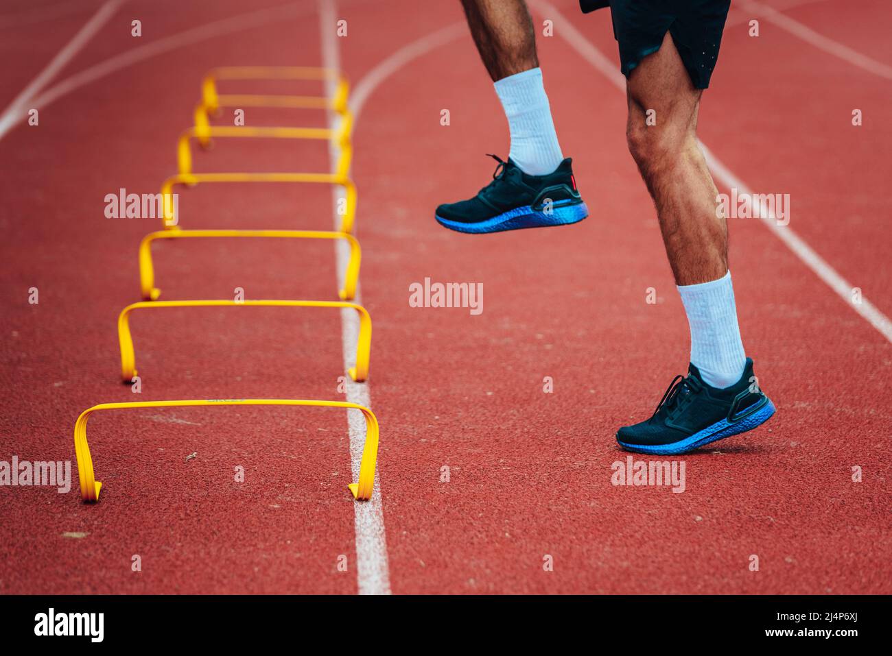 Male runner exercising and jumping on athletic track. Sport photo, warm ...