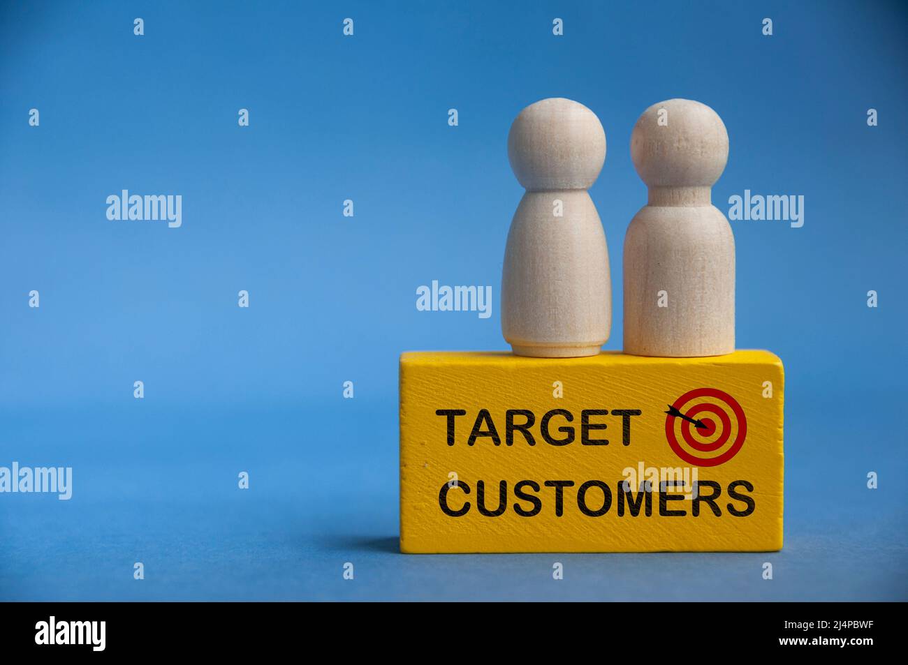 Target customers text on yellow wooden block with model wooden dolls on ...