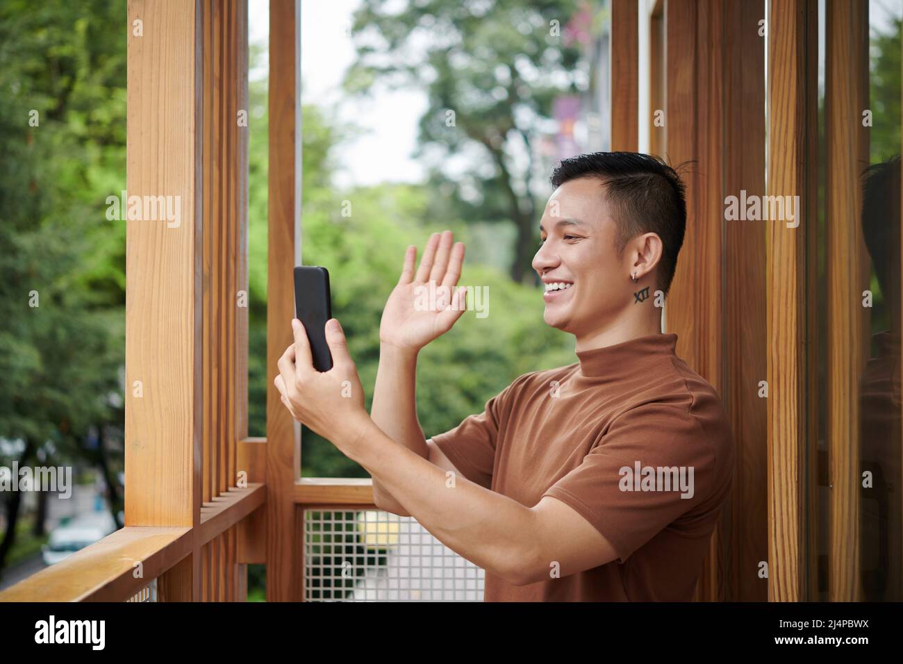 Positive young man waving with hand when video calling his friend or ...