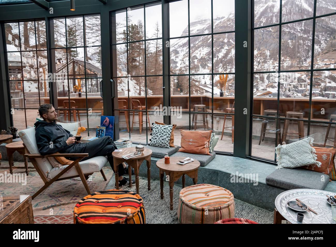 Tourist having coffee while looking at mountains from window in resort ...