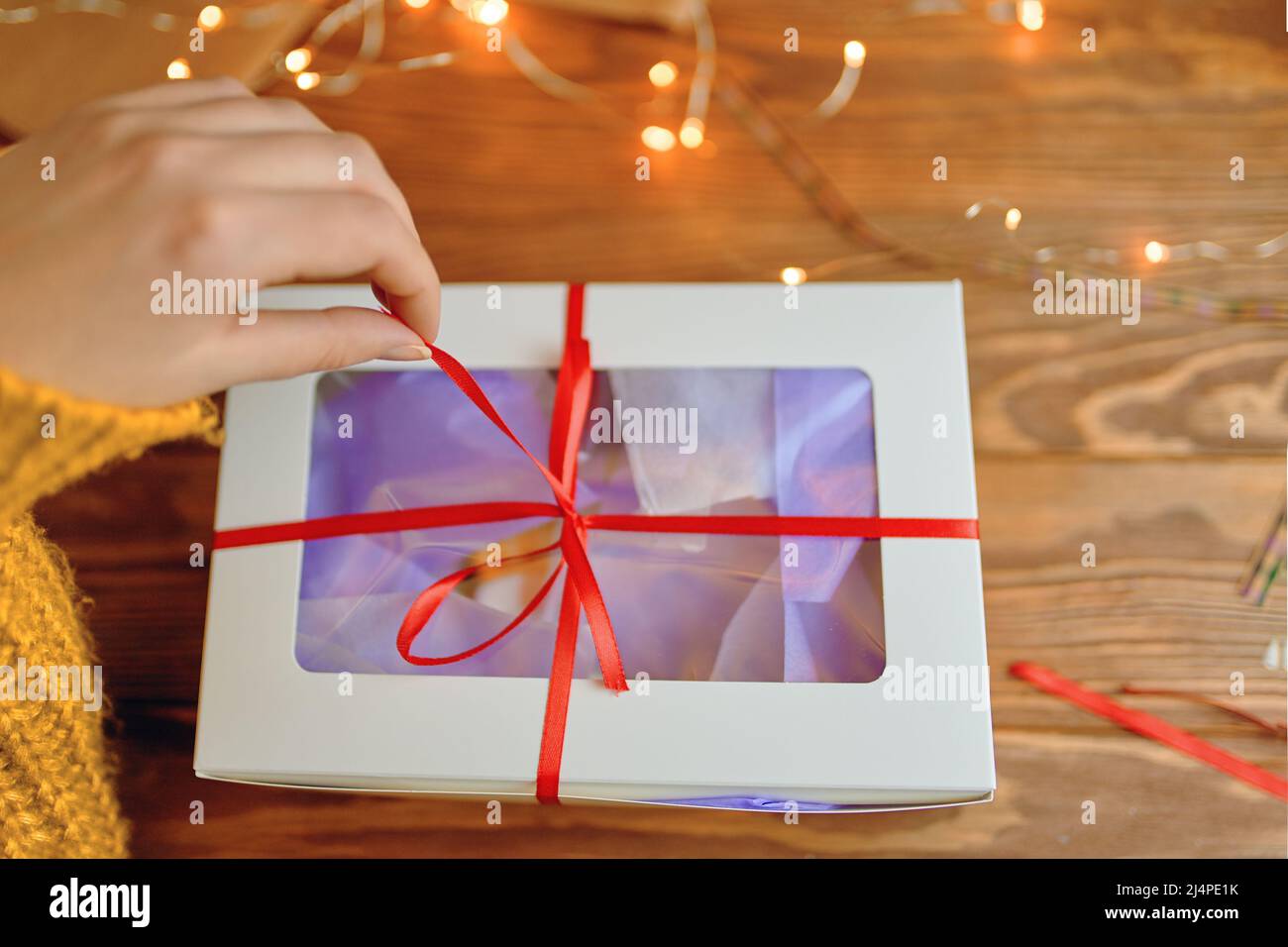 Close-up of woman's hand pulling ribbon from gift box Stock Photo - Alamy