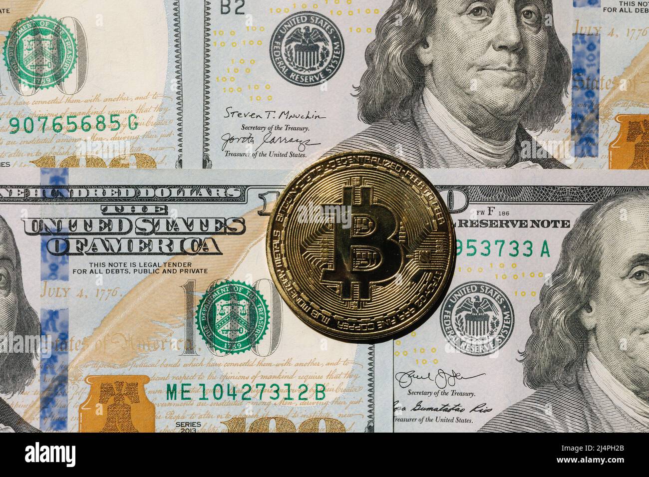 Golden shiny bitcoin crypto currency coins on one hundred US dollar ...