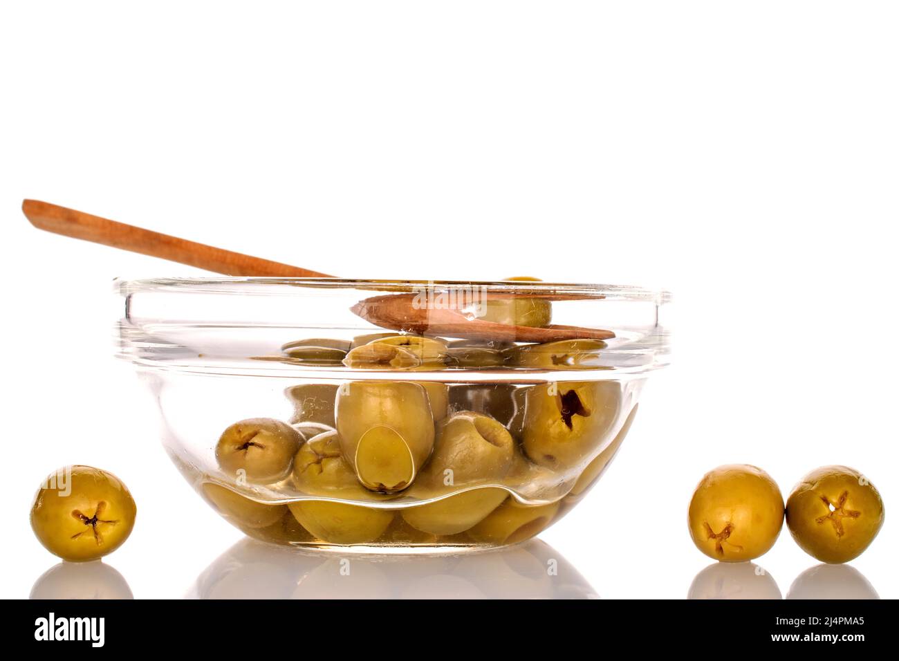 Several spicy tasty organic pickled green olives lie in a glass saucer ...