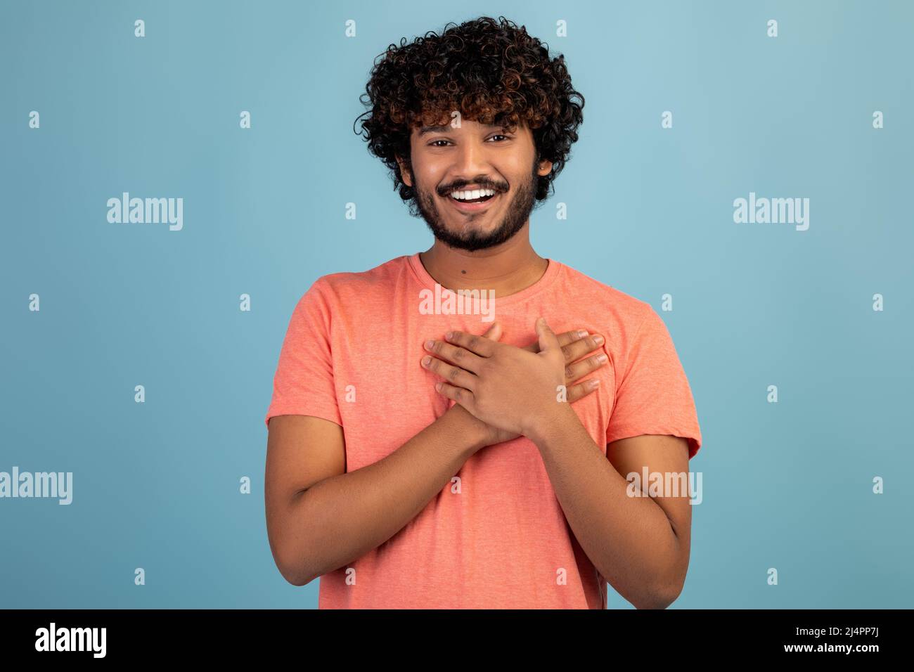 Cheerful indian man holding hands over chest Stock Photo - Alamy