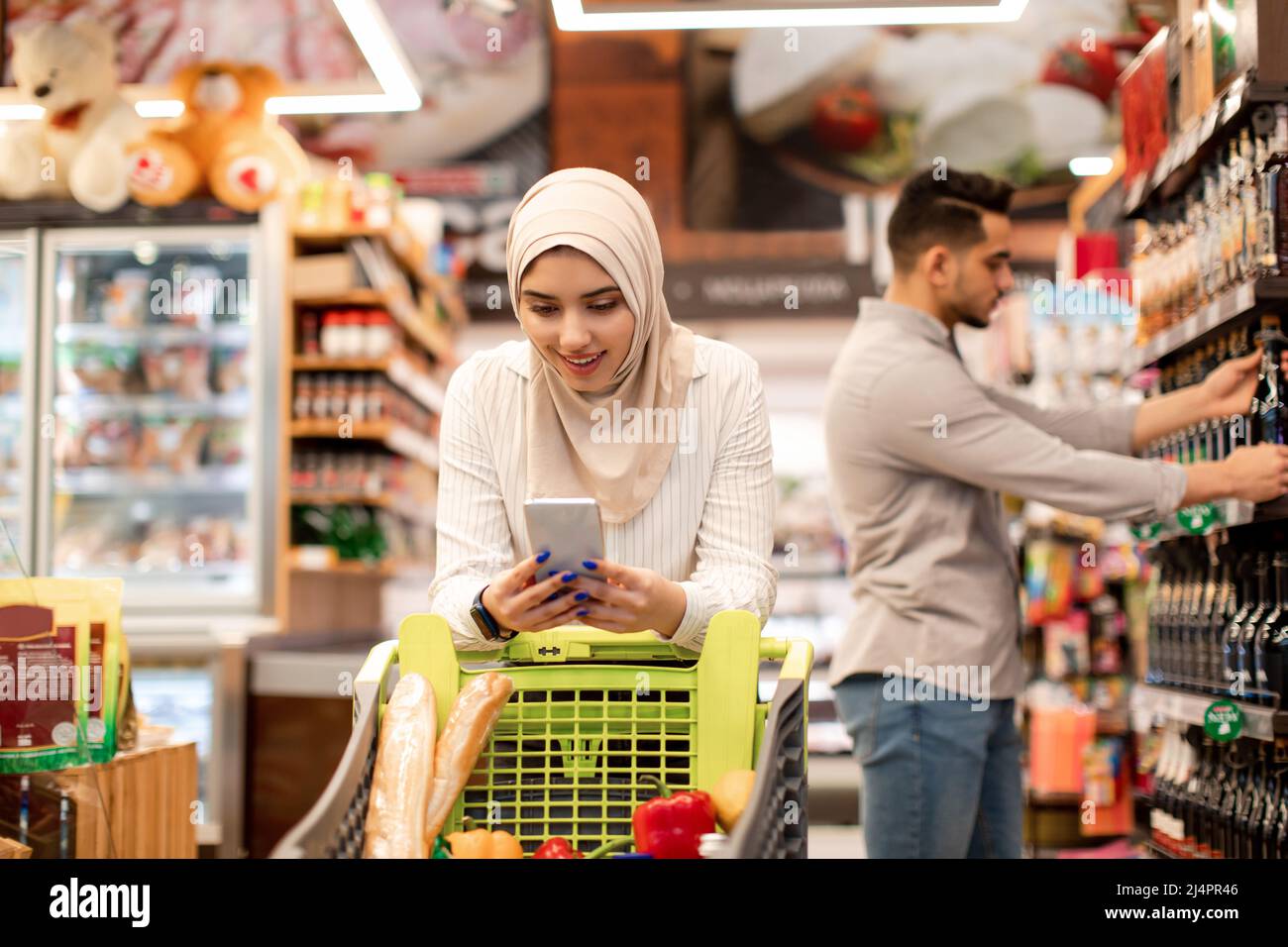 Middle Eastern Lady Shopping Groceries Using Phone Walking In ...