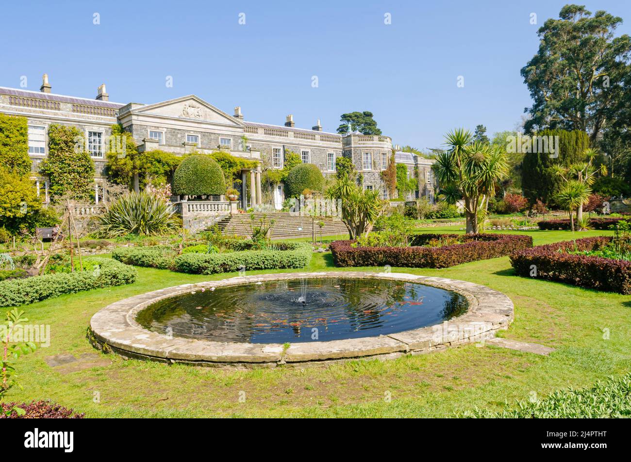 Lawn, palm trees, bushes and pond in the gardens of a stately home ...