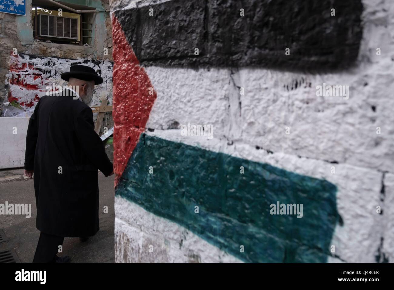 An orthodox Jew walks by a Palestinian flag spray-painted on a wall by ...