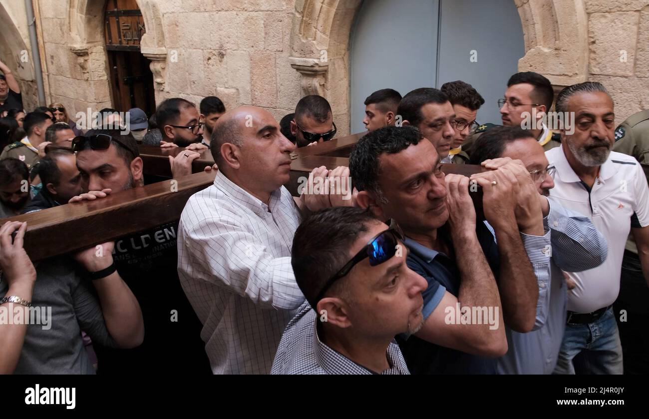 Christian Arab worshipers carry a large wooden cross as they take part ...