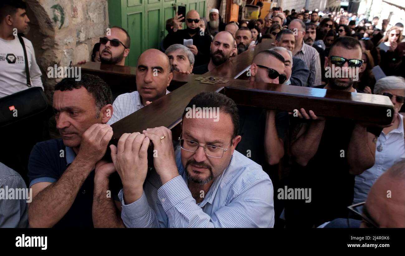 Christian Arab worshipers carry a large wooden cross as they take part ...