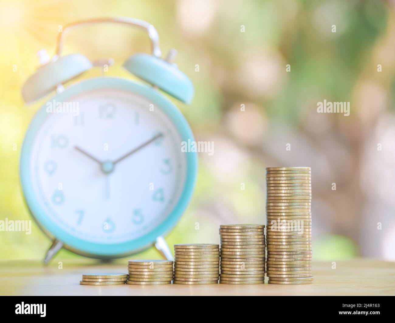 Gold coins and home in front off alarm clock.Concept for loan, property ...