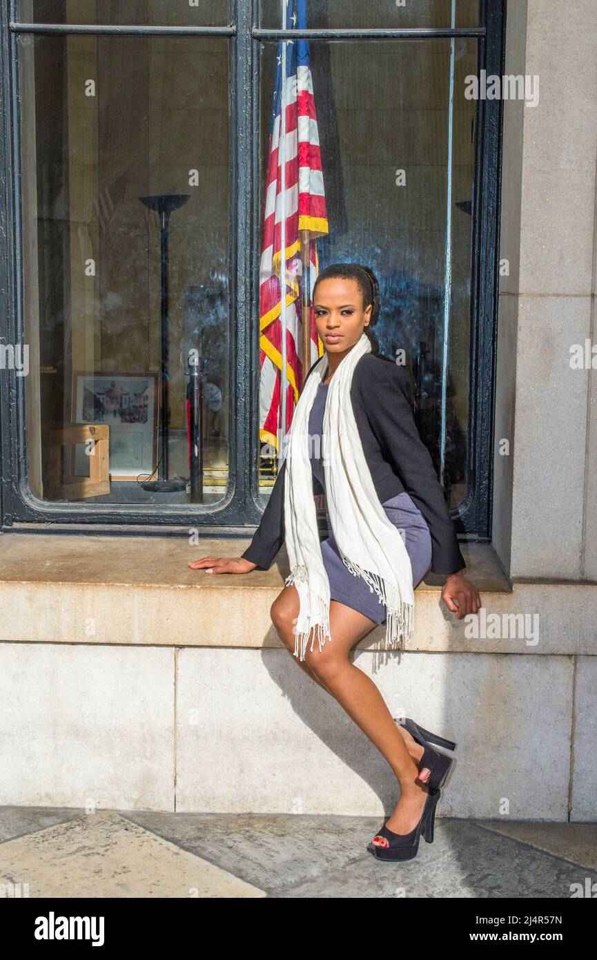 Dressing in a black jacket, a gray fitted dress, open toe high heels, a ...