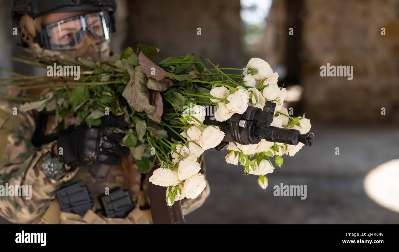 Caucasian woman in military uniform holding a machine gun and a bouquet ...
