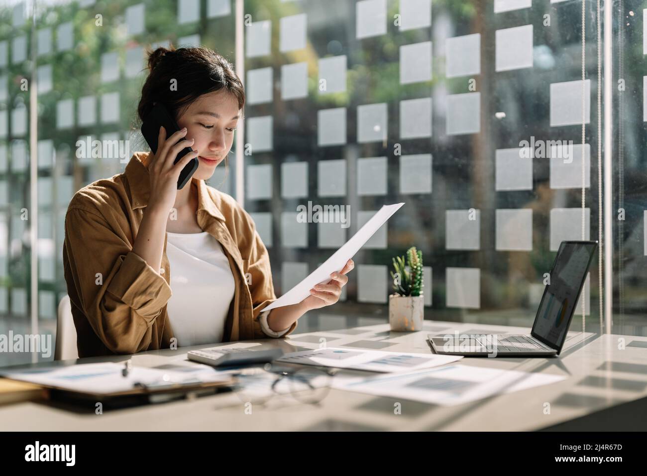 Young asian accountant calling marketing consultants and using laptop ...